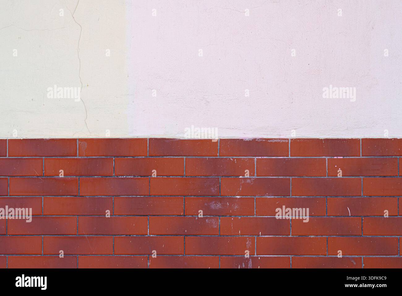 Half of the red brick wall is painted over with white plaster. Abstract ...