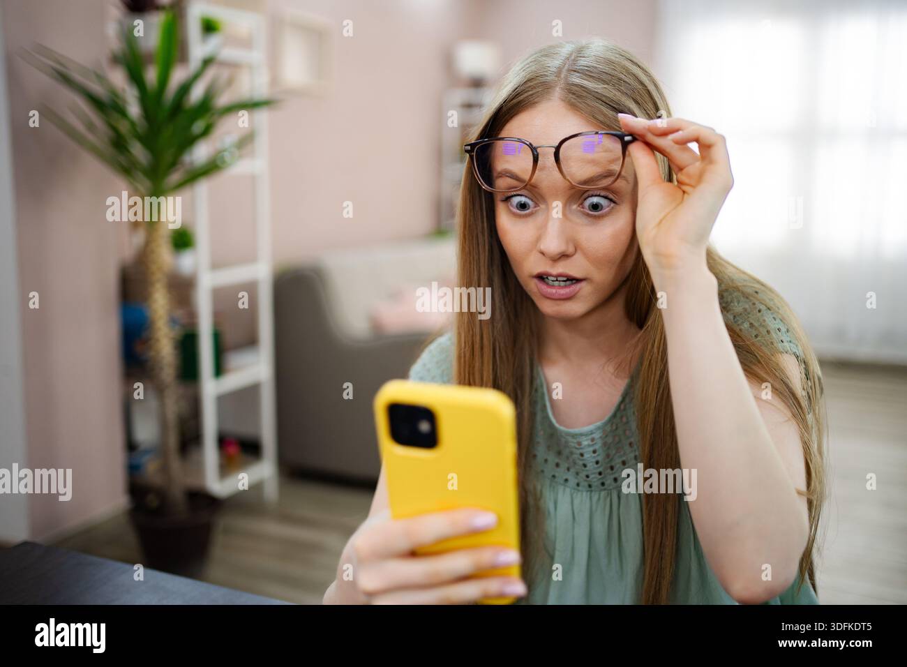Surprised reaction of a young woman while using her smartphone indoors ...