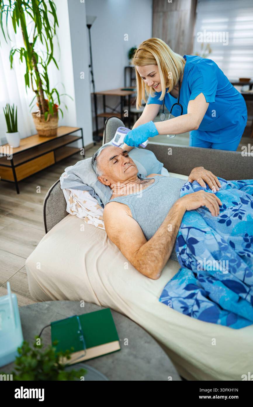 Caregiver checks temperature of elderly man at home Stock Photo - Alamy