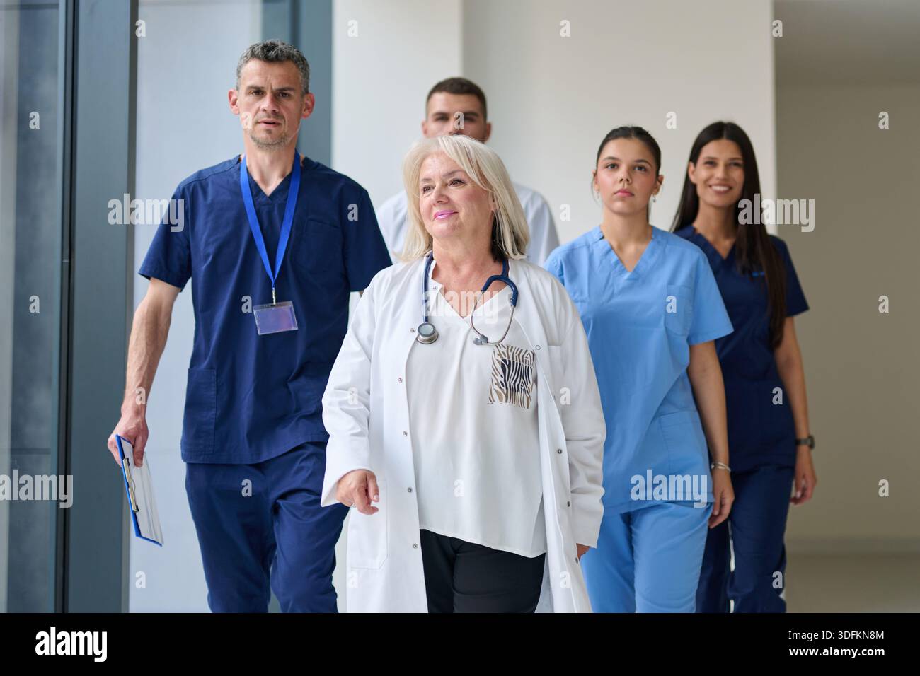 Group of medical professionals walking through a hospital corridor with ...