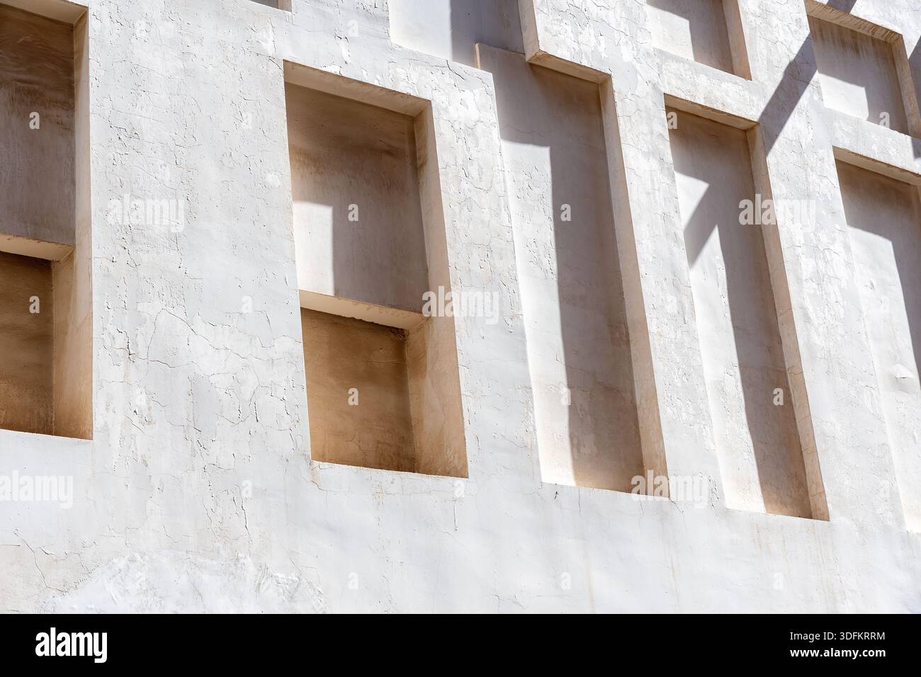 White textured architectural wall with geometric recesses and harsh ...