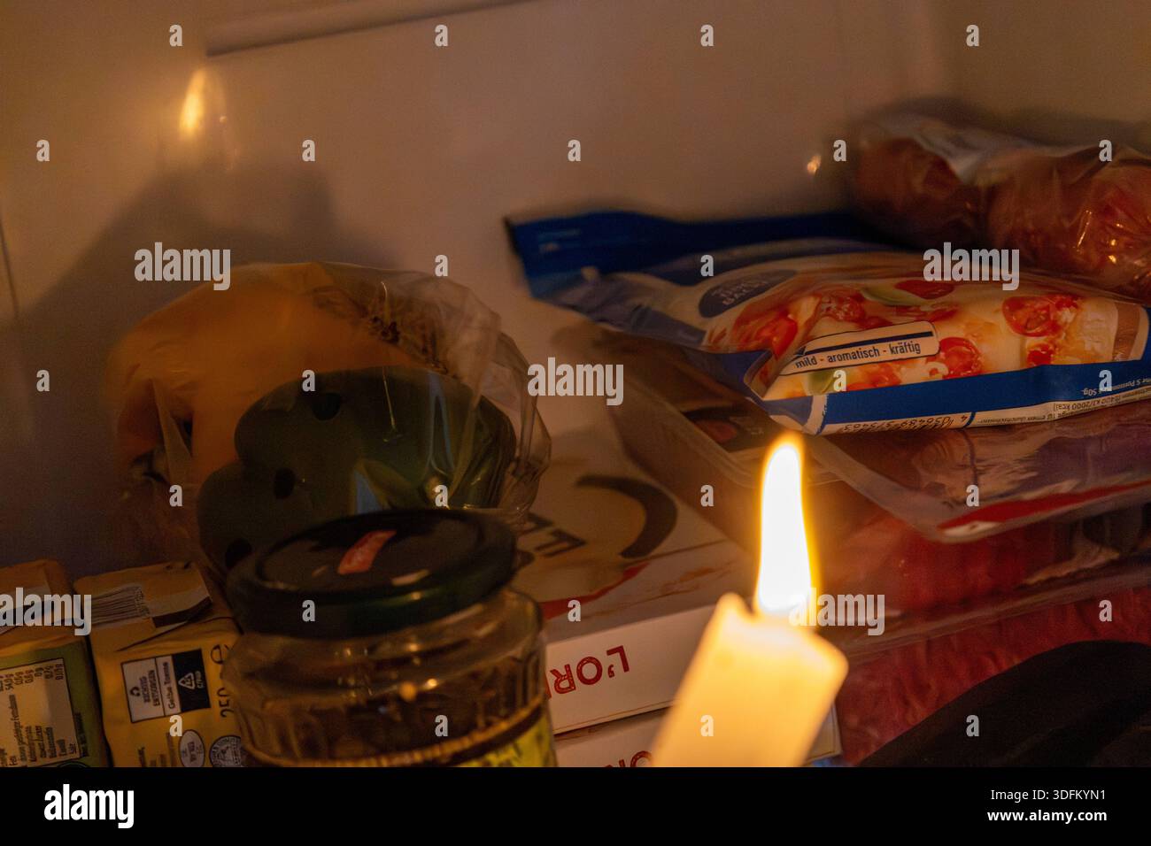 Blackout Symbolbild: Ausleuchten eines dunklen Kühlschranks mit Kerze ...