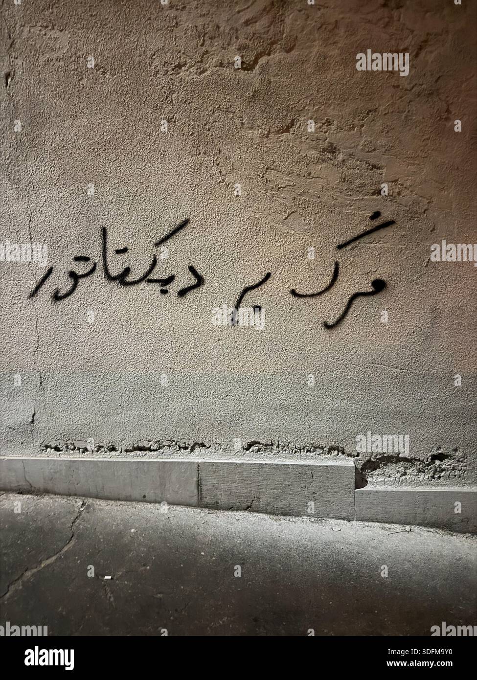 A slogan is written on a wall reading in Farsi: "Death to dictator" in ...