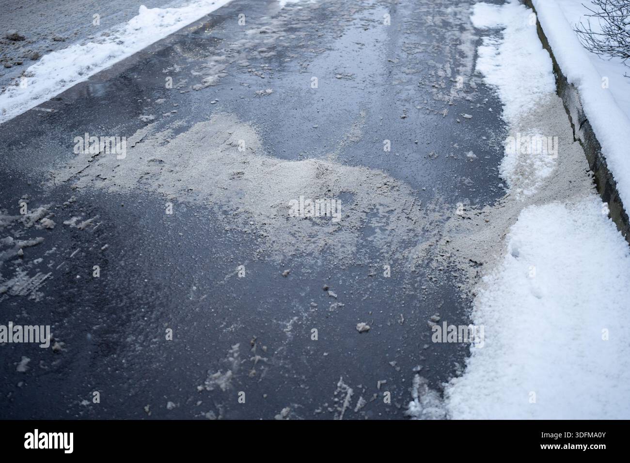 Deicing chemicals on snowy street in winter. Slippery road sprinkled ...