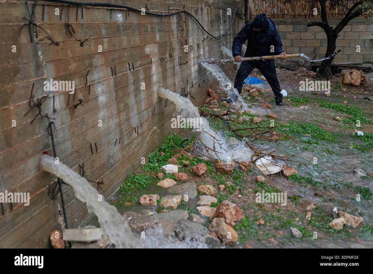 A man clears for the water flow to drain flooded houses during a ...
