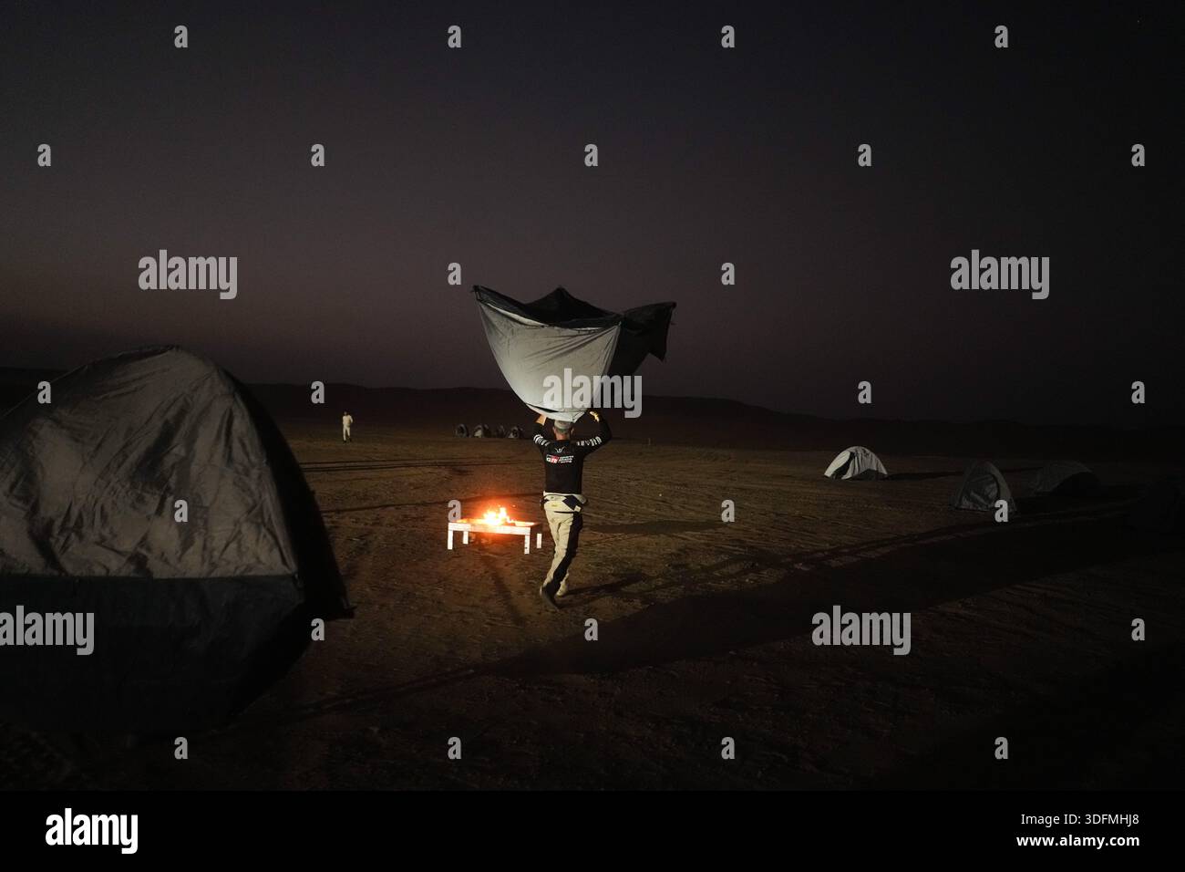 A driver carries his tent for a bivouac after the ninth stage of the ...