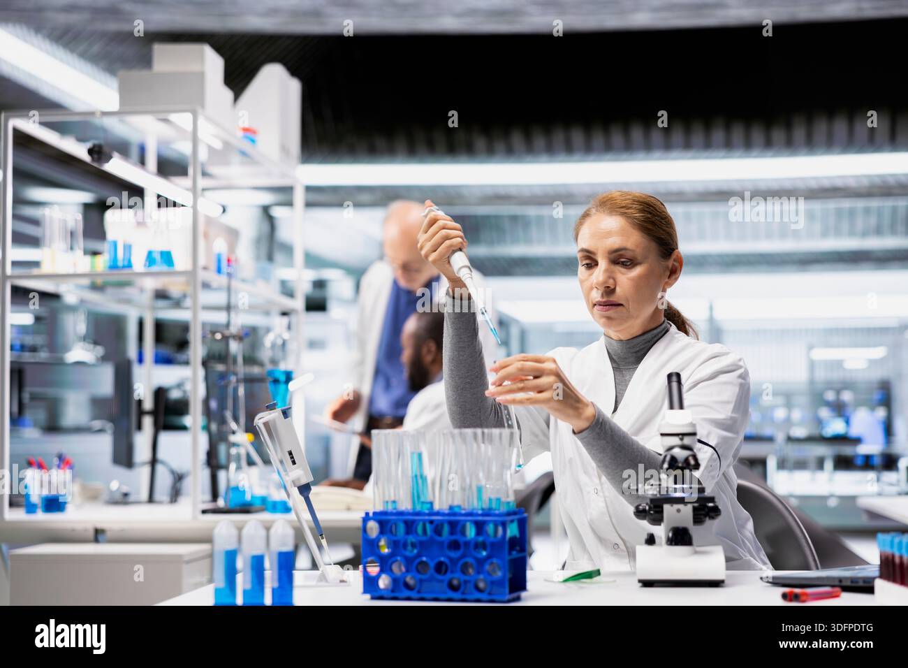 Lab professional pipetting agent into blue test tube sample to improve ...