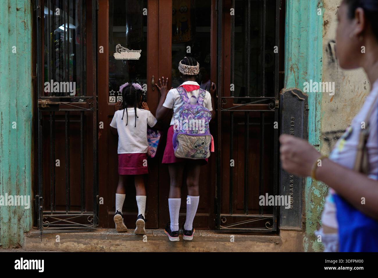 Schoolgirls look through the windows of a restaurant in Havana, Tuesday ...