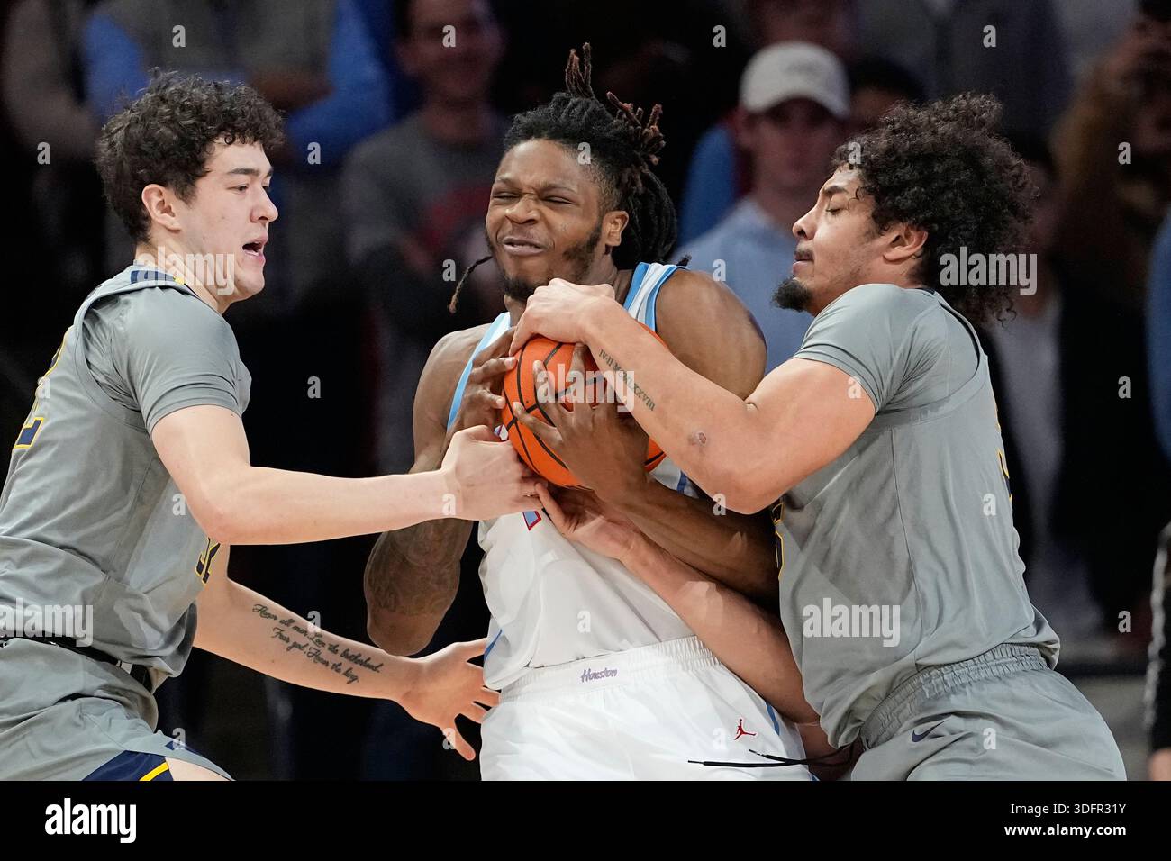 Houston's Joseph Tugler, center, is fouled by West Virginia's Harlan ...