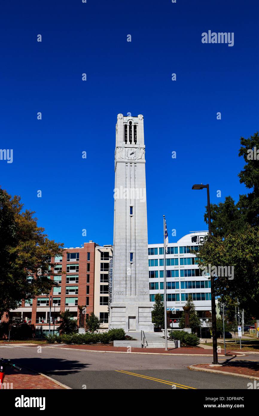 Tall stone clock tower rising above city buildings under deep blue sky ...