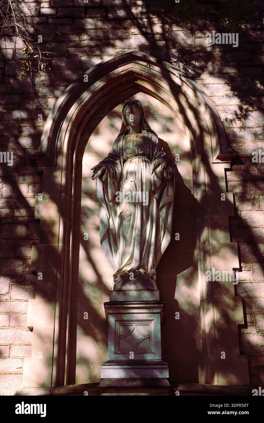 Religious statue of Virgin Mary standing in a stone arch niche with ...