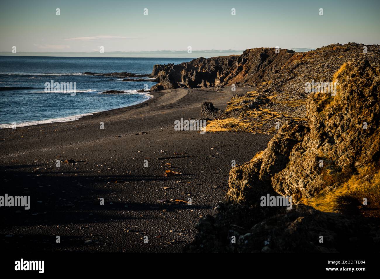 View of black sands embrace the rugged, dark cliffs where the sea ...