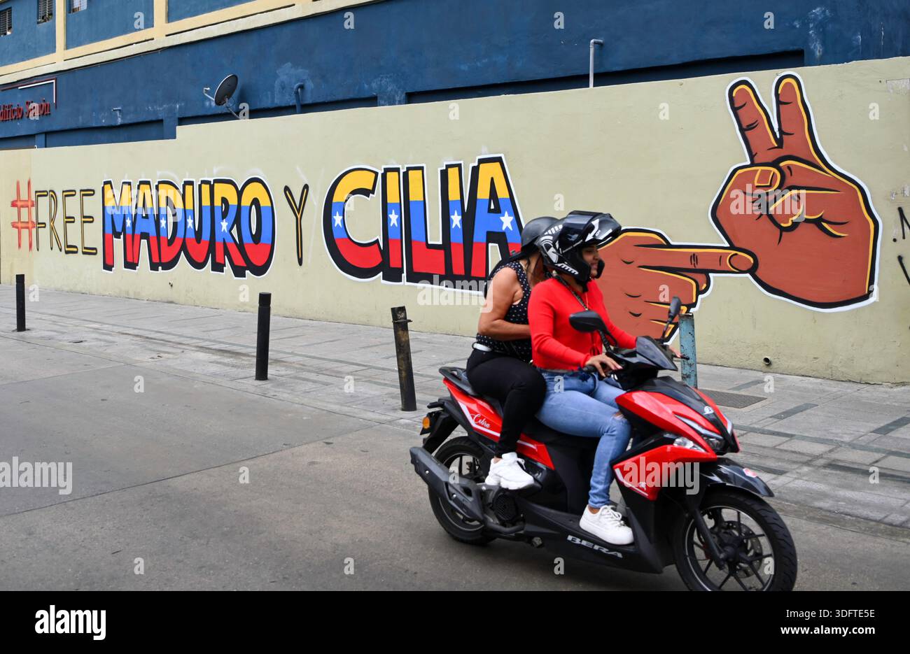 (260114) -- CARACAS, Jan. 14, 2026 (Xinhua) -- People ride a motorcycle past a graffiti wall in ...