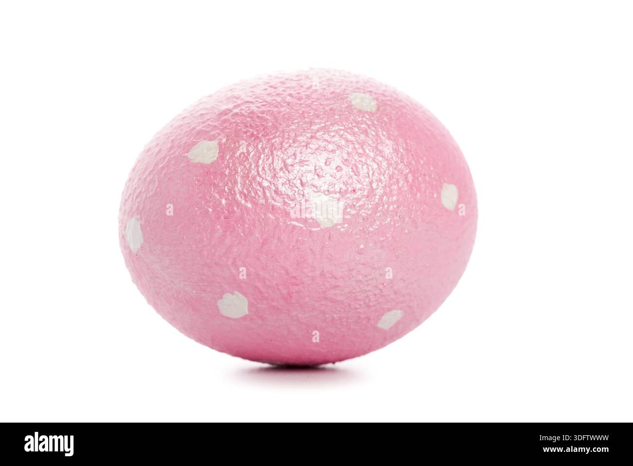 Pink round object with white dots on a plain background during a simple ...