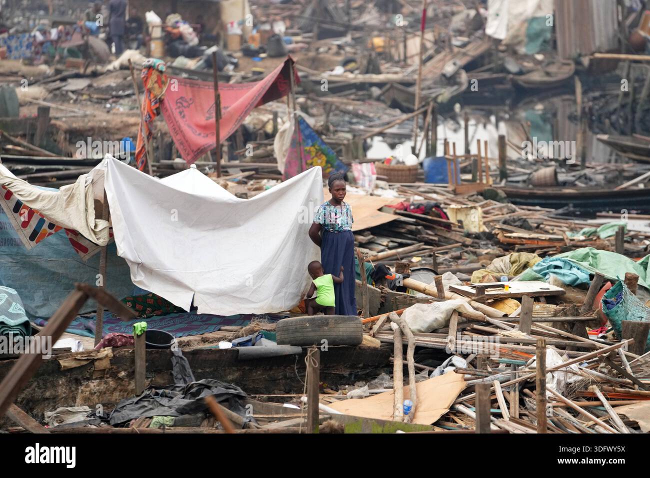 A woman stands on the ruins of her demolished stilts house by ...