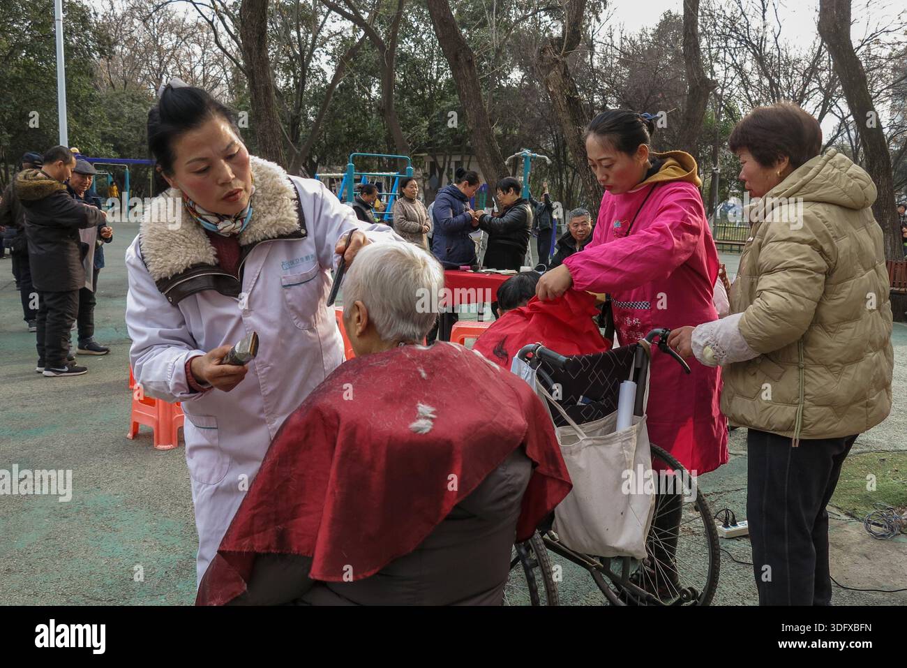 In Wenfeng Park, a volunteer gives a haircut to an elderly person in a ...