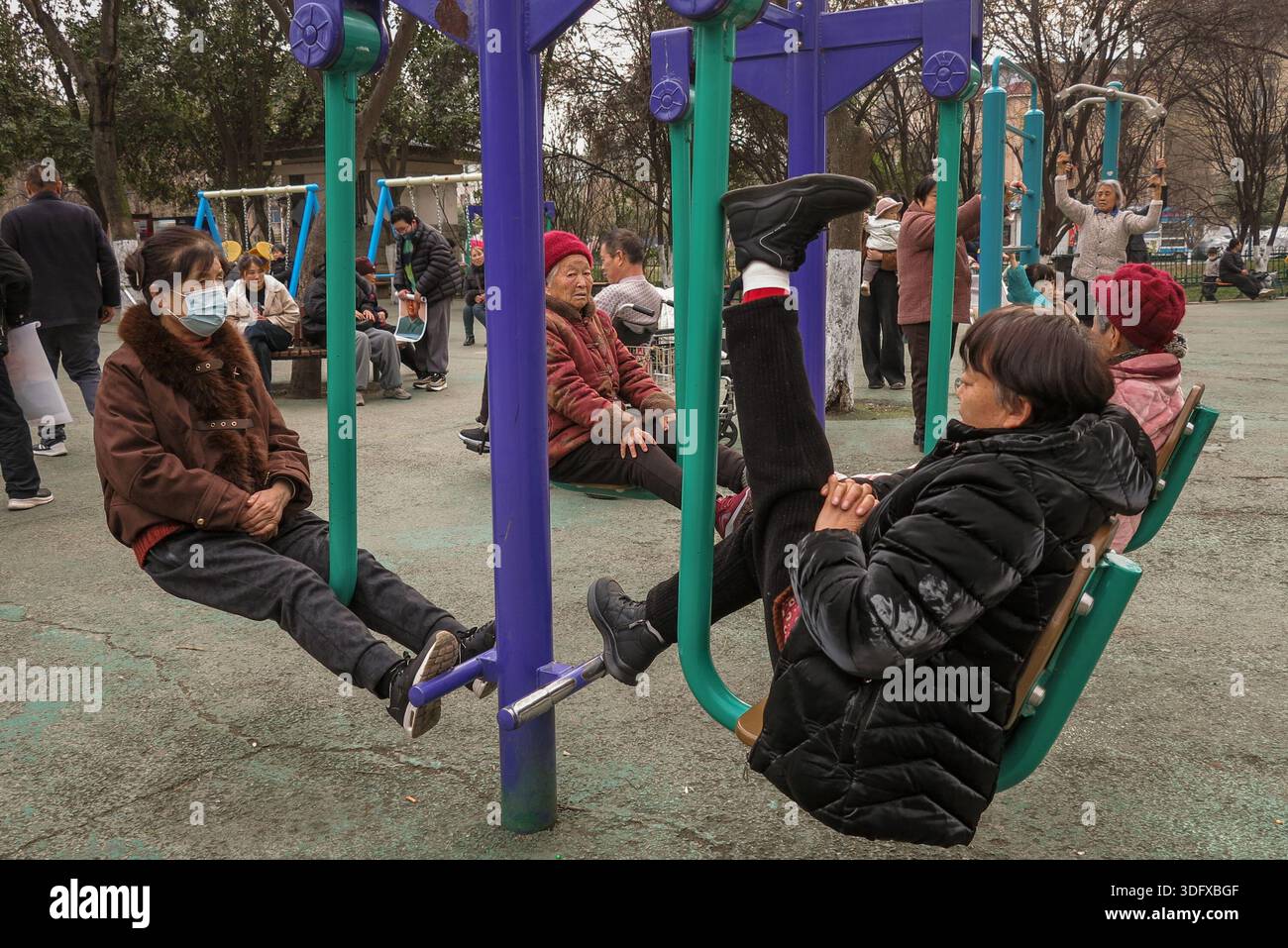 Delivery riders wait on their scooters at a street corner, with a ...