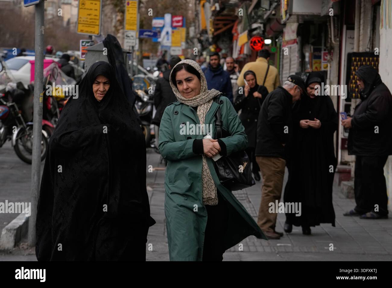 People walk on a sidewalk in downtown Tehran, Iran, Wednesday, Jan. 14 ...