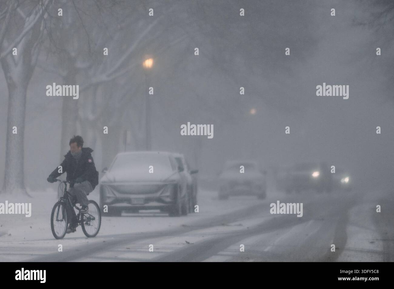 A person rides a bicycle through blowing snow, Wednesday, Jan. 14, 2026 ...