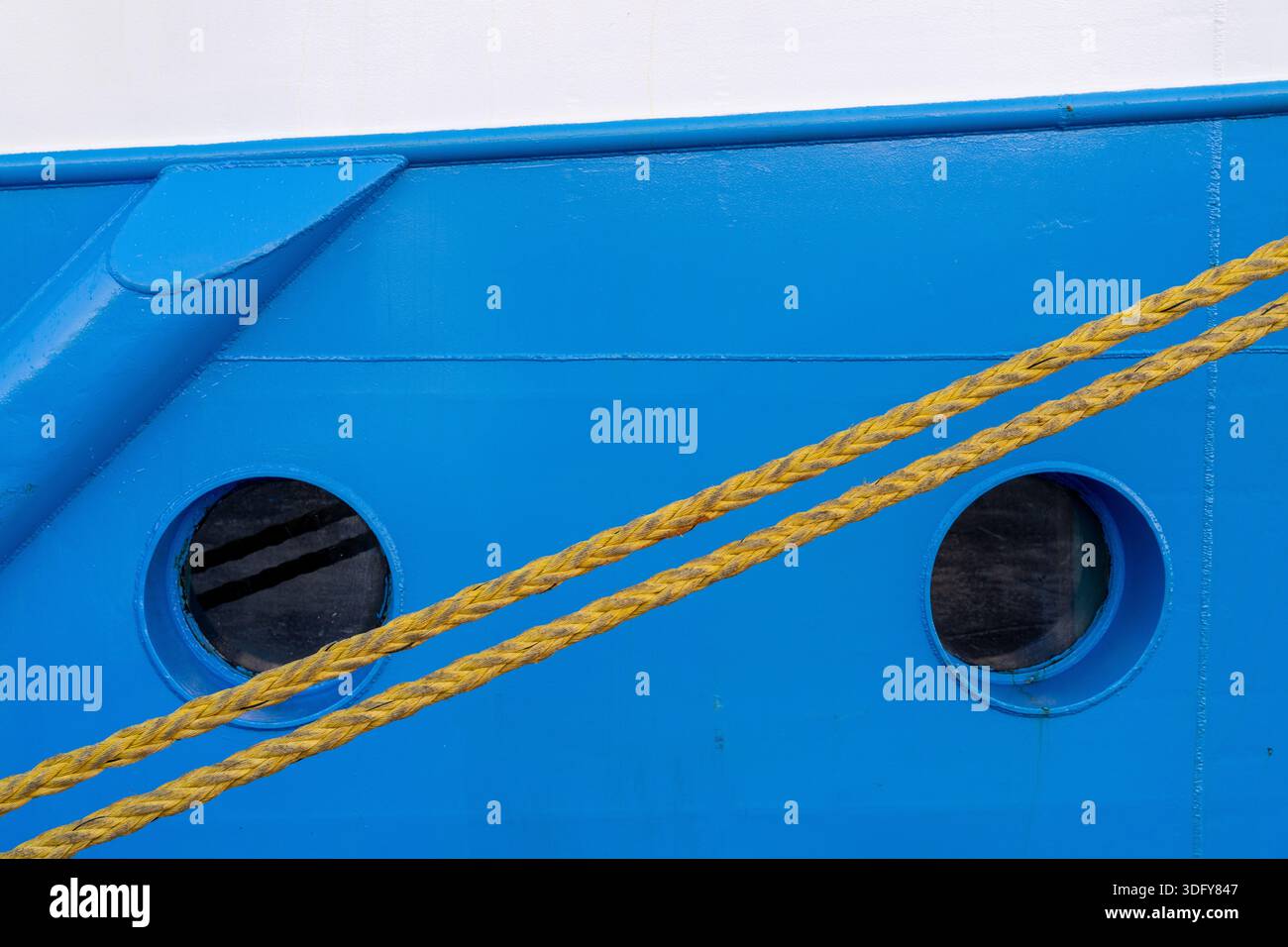 A thick berthing rope is secured across the bow of a blue and white ...