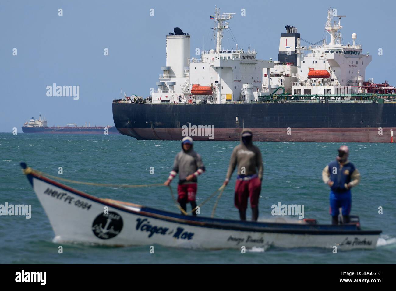 Fishermen pass an oil tanker in the Gulf of Venezuela off the shore of ...