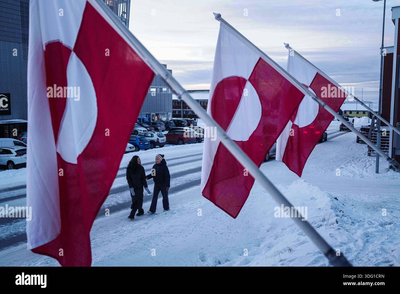 Women walk on a street in front of national flags in Nuuk, Greenland ...