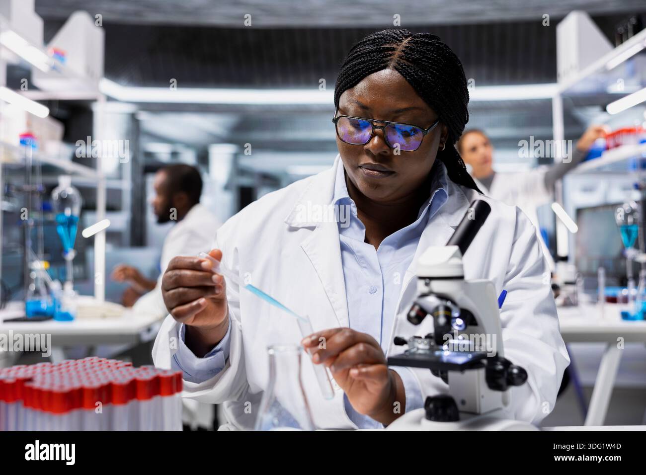 Histology technician in laboratory pipets agent into blue test tube ...