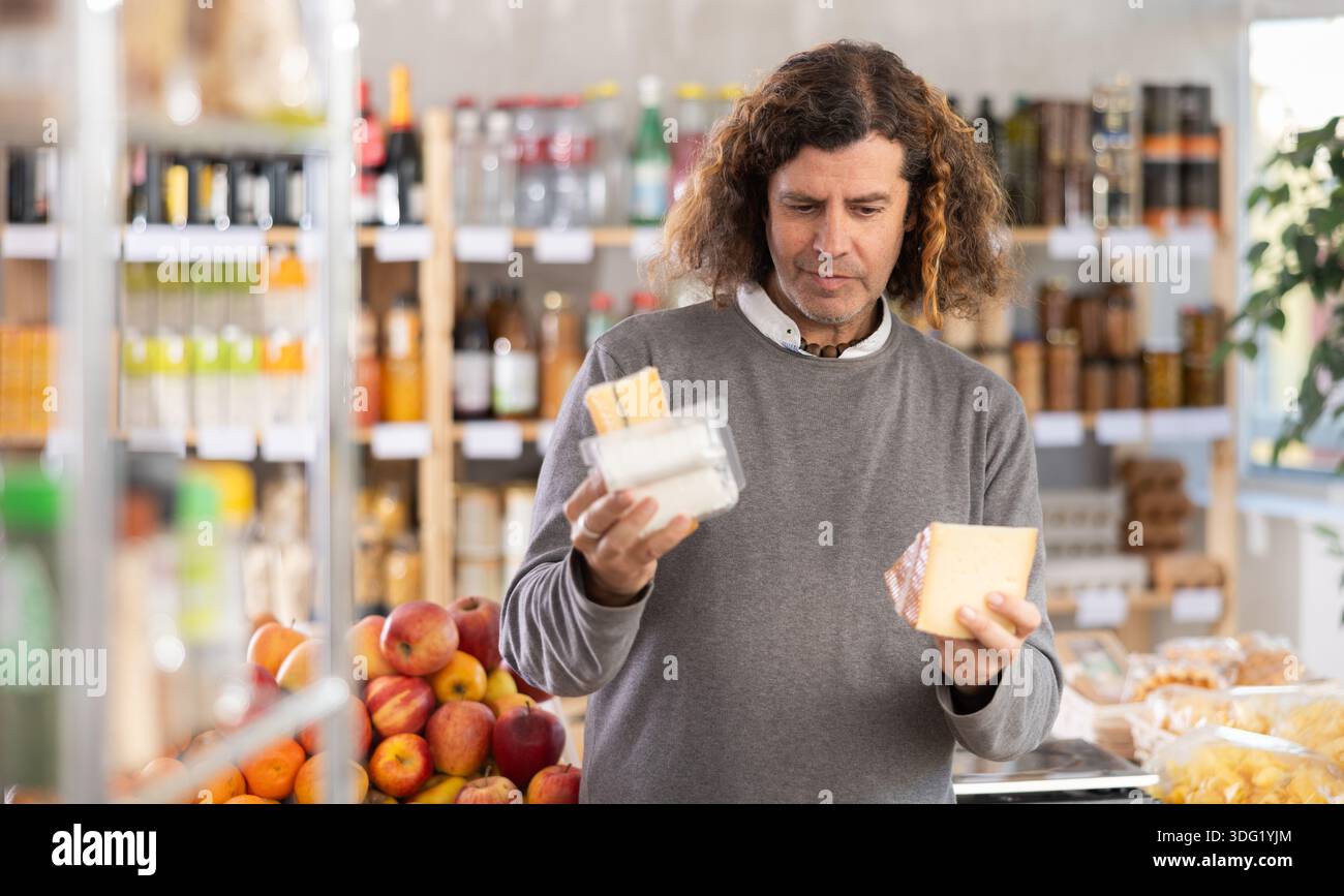 Choose cheese in supermarket - man chooses what cheese to buy in the ...