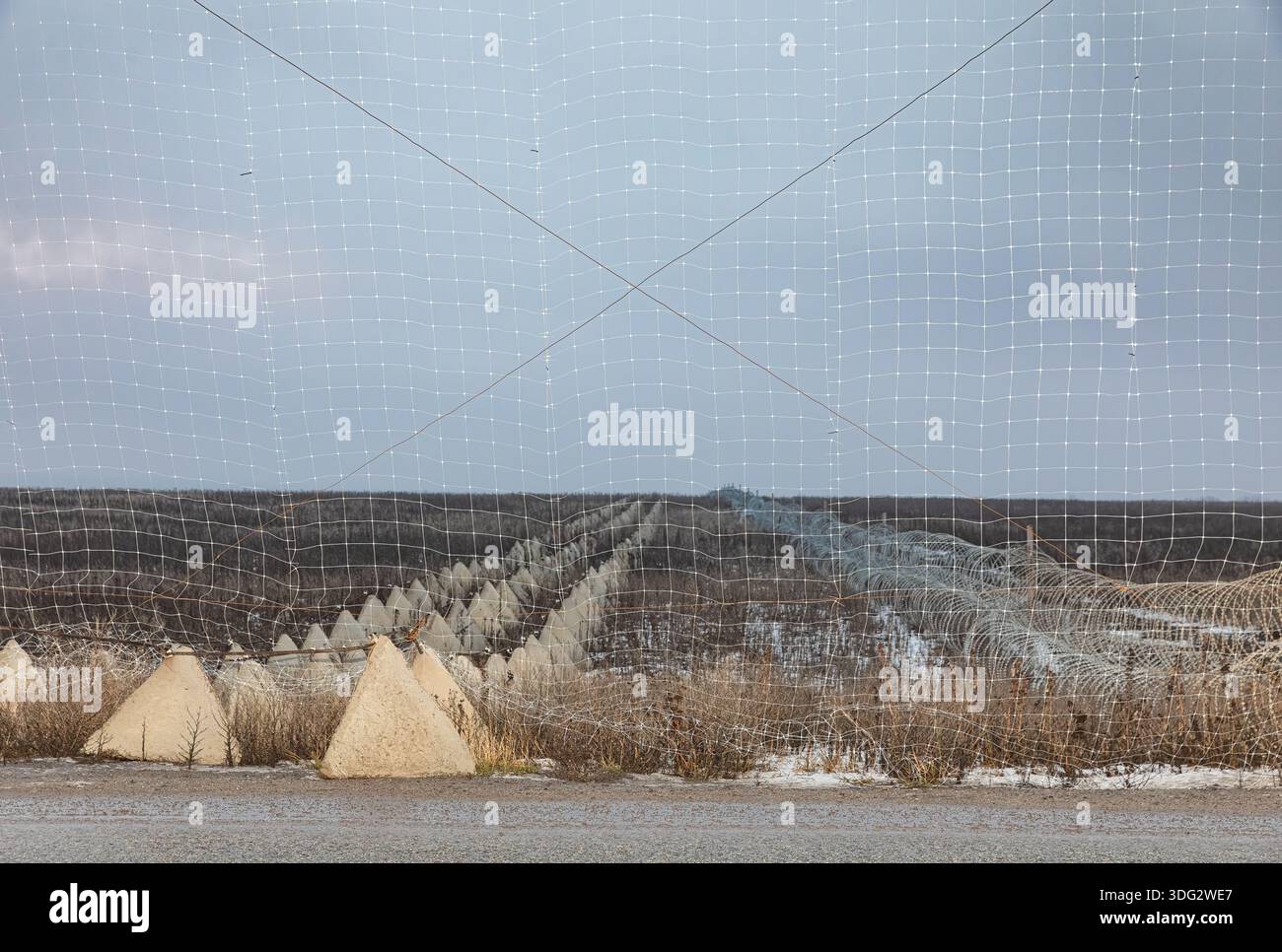 An anti-drone net is seen covering the foreground. Rows of concrete ...