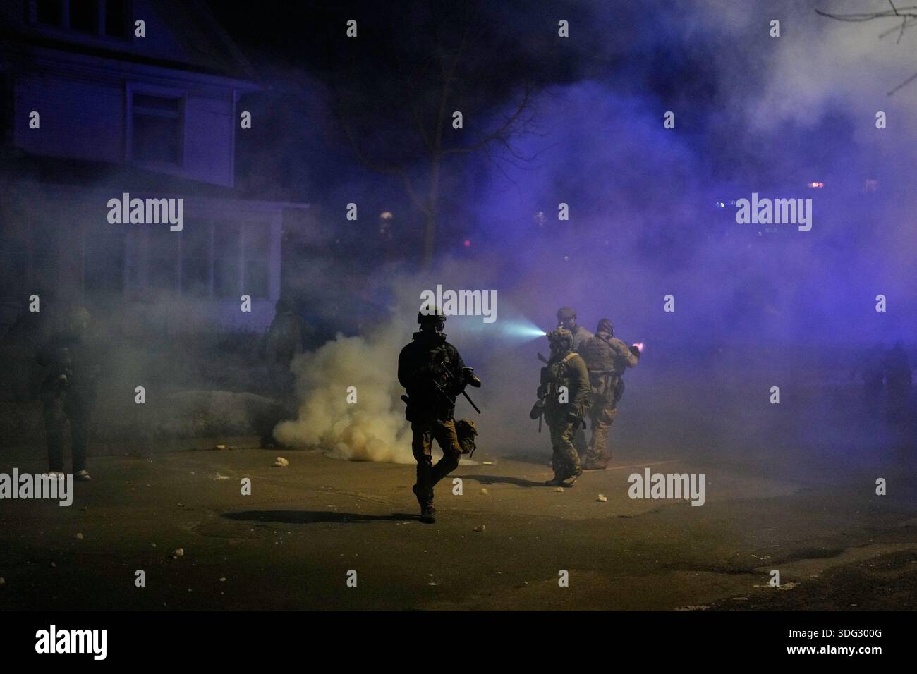 Law enforcement officers stand amid tear gas at the scene of a reported ...