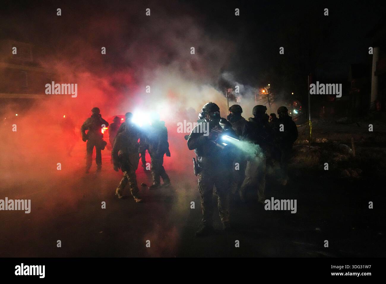 Law enforcement officers stand amid tear gas at the scene of a reported ...