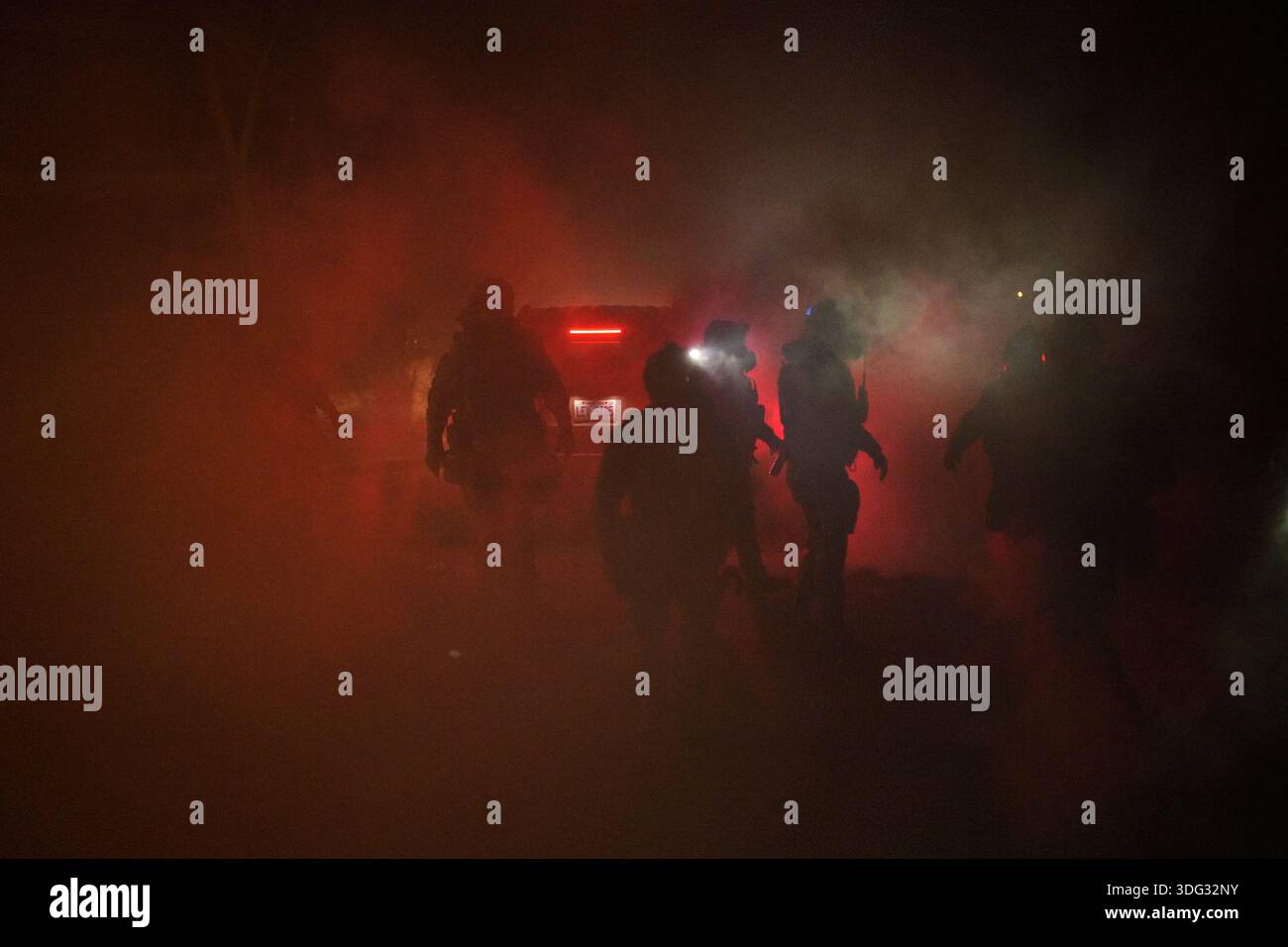 Law enforcement officers stand amid tear gas at the scene of a reported ...