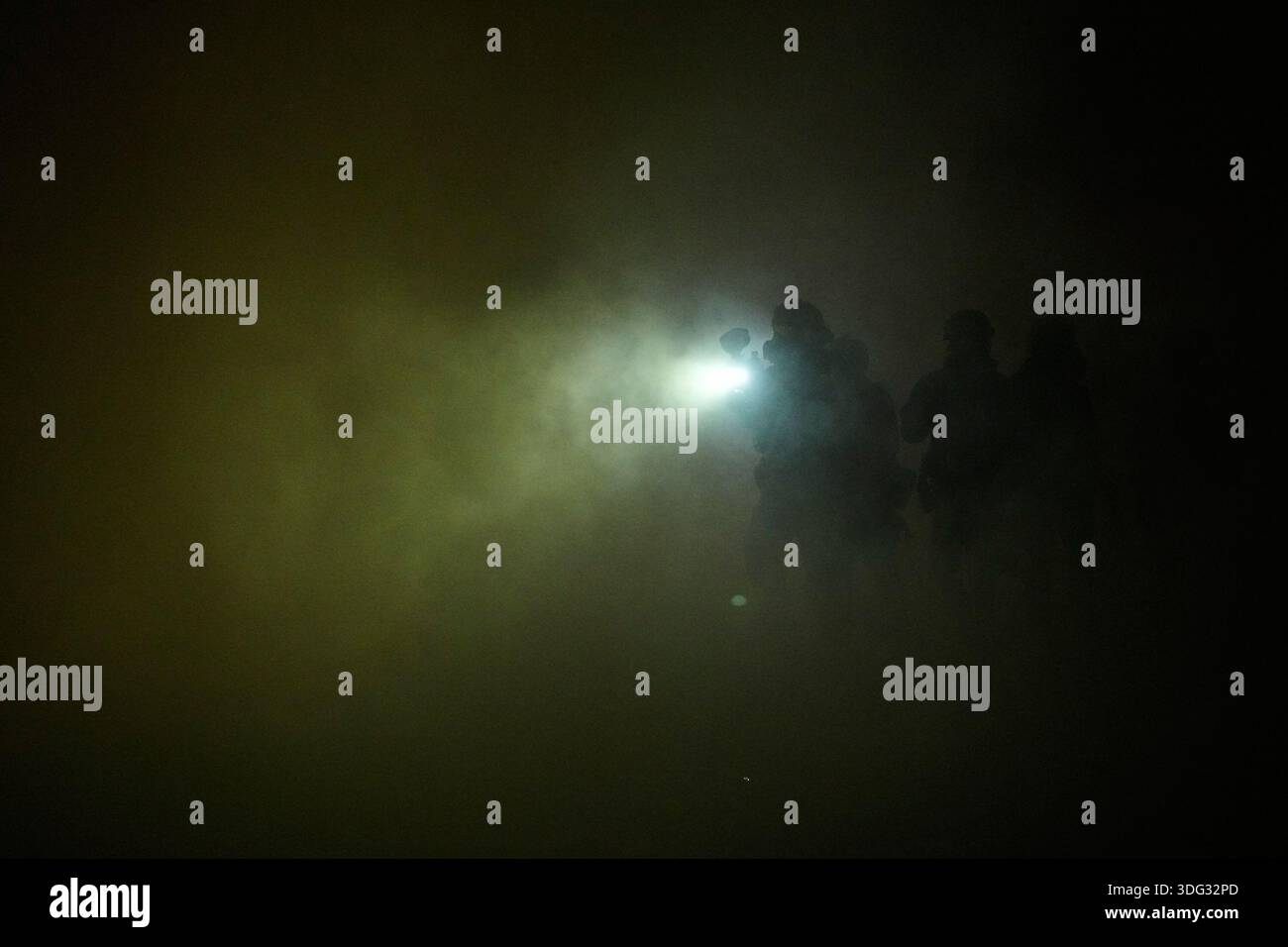 Law enforcement officers stand amid tear gas at the scene of a reported ...