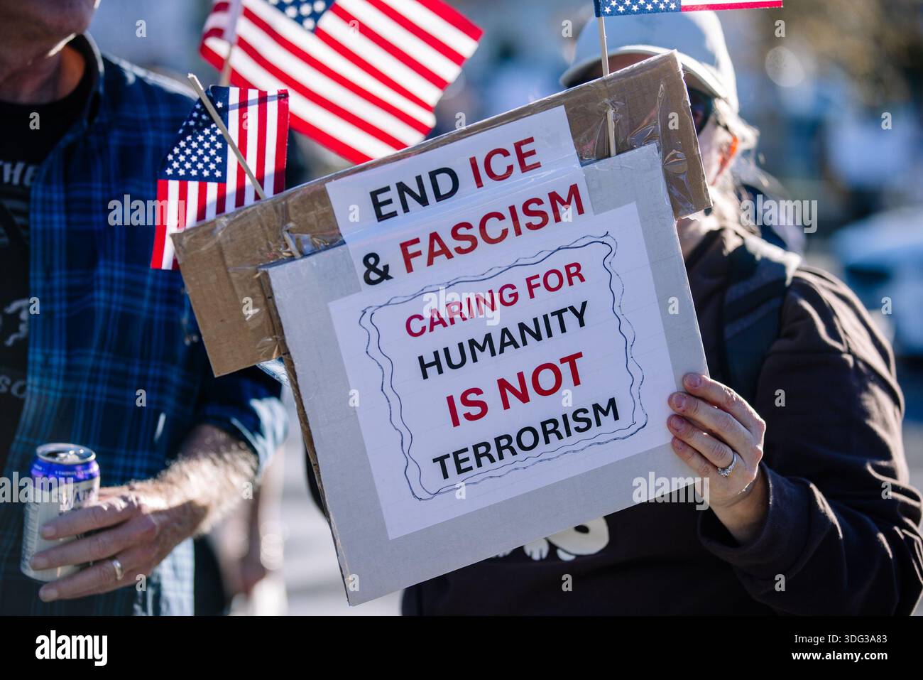 A protester holds a sign reading “End ICE & Fascism” and “Caring for ...