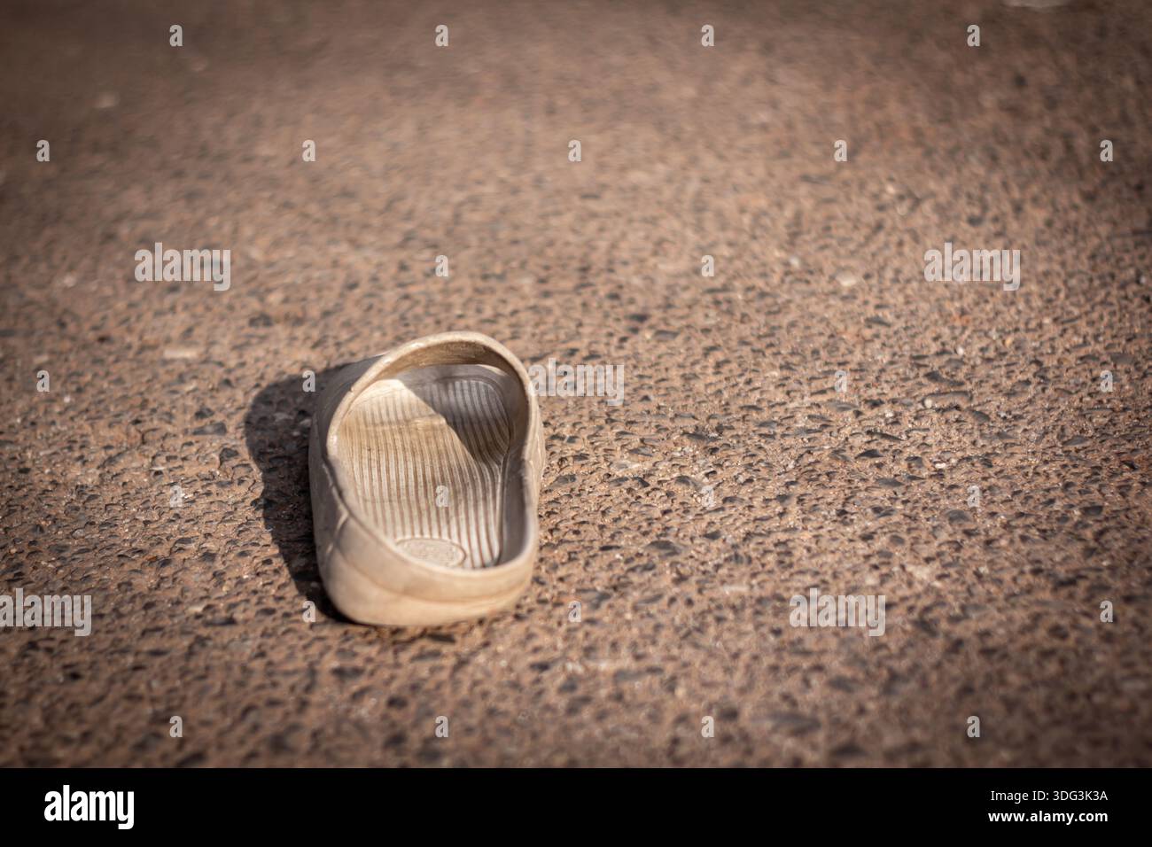 Single shoe abandoned on concrete symbolizing loss, loneliness, and ...