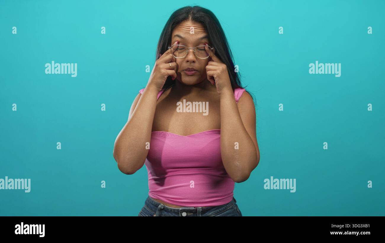 Woman adjusting glasses with hands raised and mouth open in turquoise ...