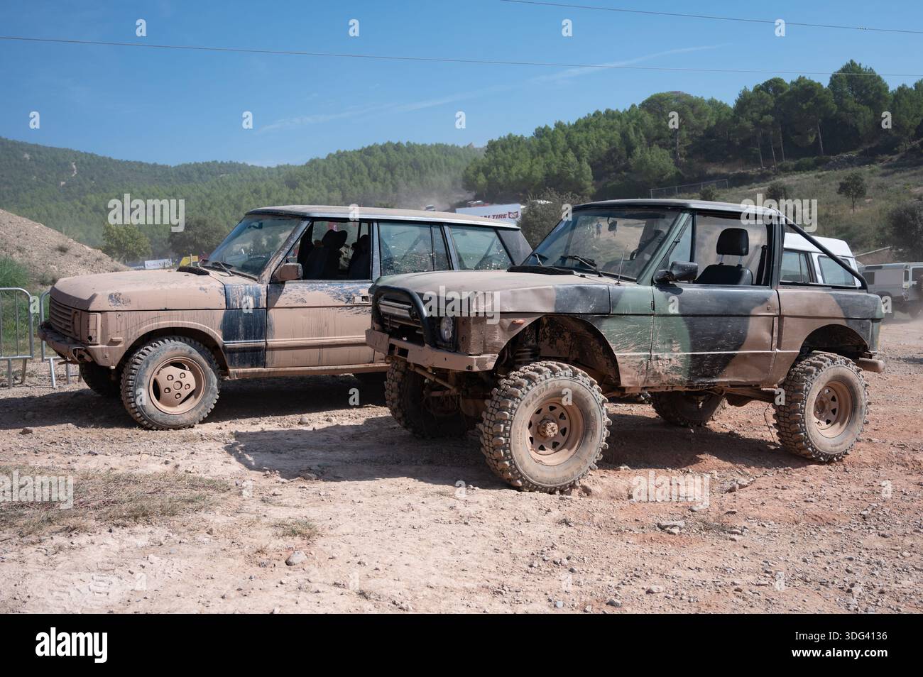 Modified camouflage bobtail Range Rover Classic alongside a muddy blue ...