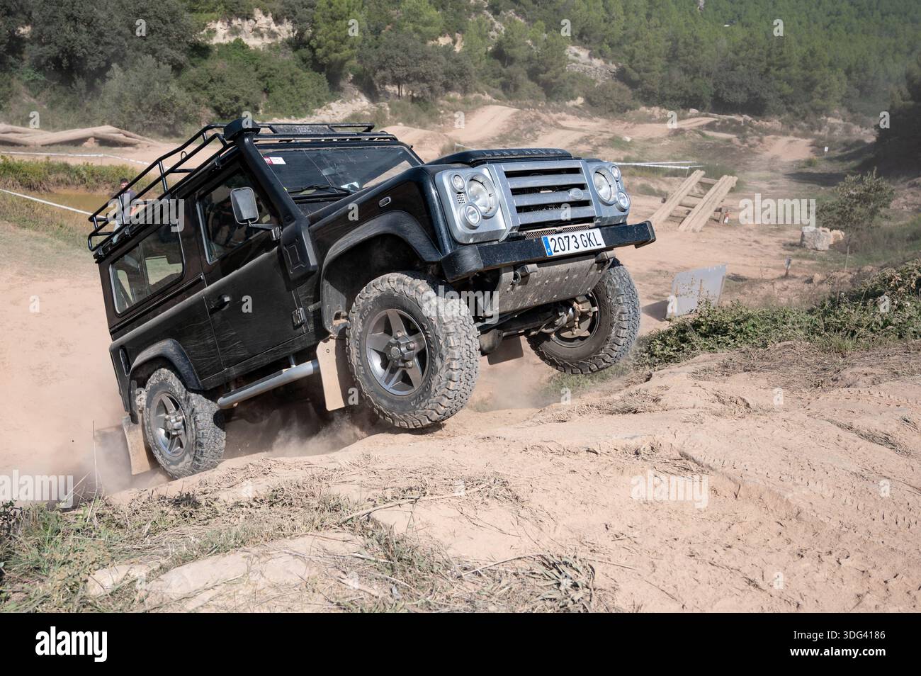 Black classic Land Rover Defender short wheelbase jumping on a dusty ...