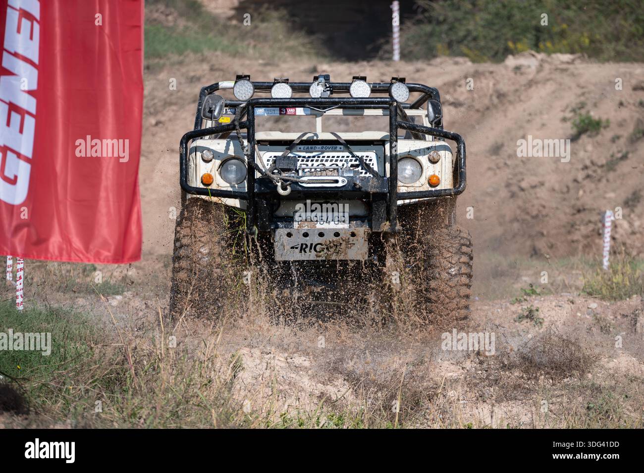Modified white Land Rover Santana Series III splashing through deep mud ...
