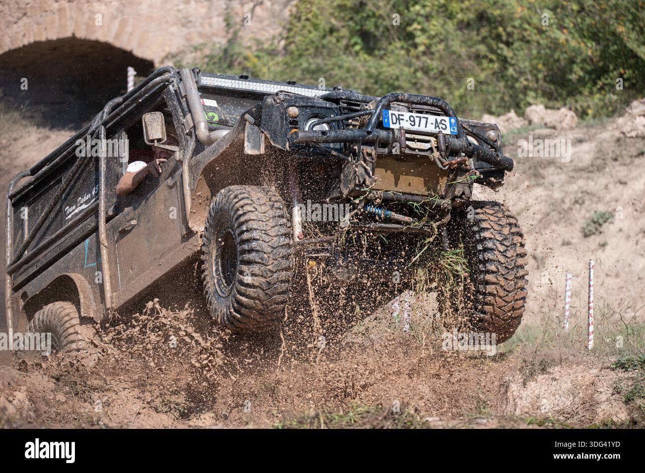 Front view of a black modified Land Rover Defender jumping over mud ...
