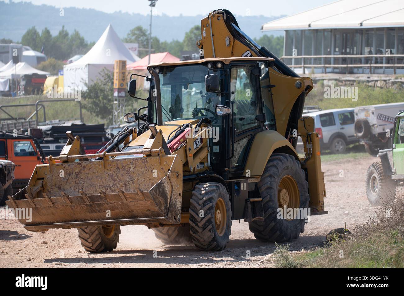 Front side view of a yellow Caterpillar 432 backhoe loader on a dirt ...