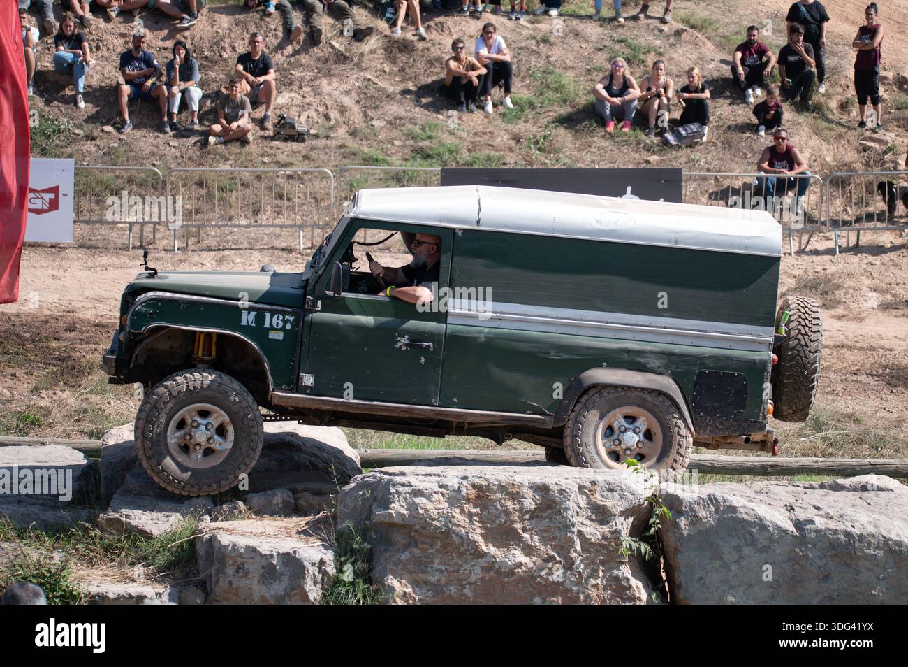Side view of a classic green Land Rover Defender 110 crawling over ...