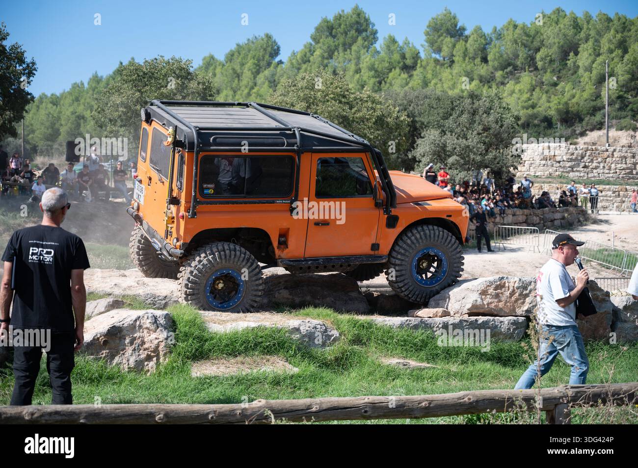 Side view of an orange Land Rover Defender 90 rock crawling. Features ...