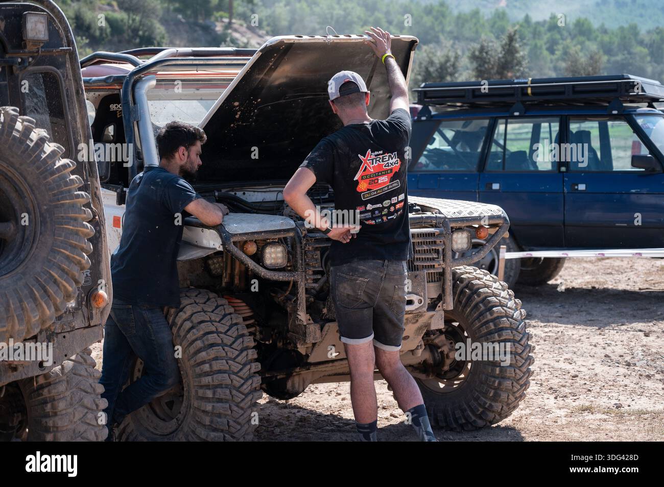 Two men inspecting the engine of a modified white Land Rover Defender ...