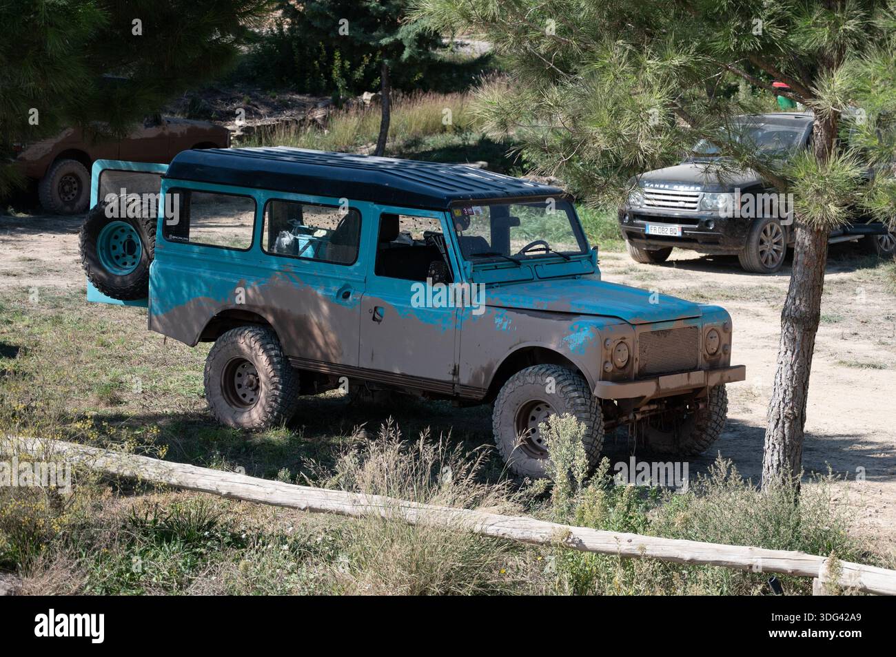 Side view of a classic blue Land Rover Defender 110 with mud splatters ...