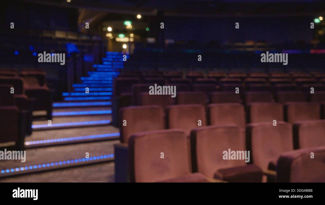 Defocused cinema auditorium with glowing blue aisle lights and soft ...