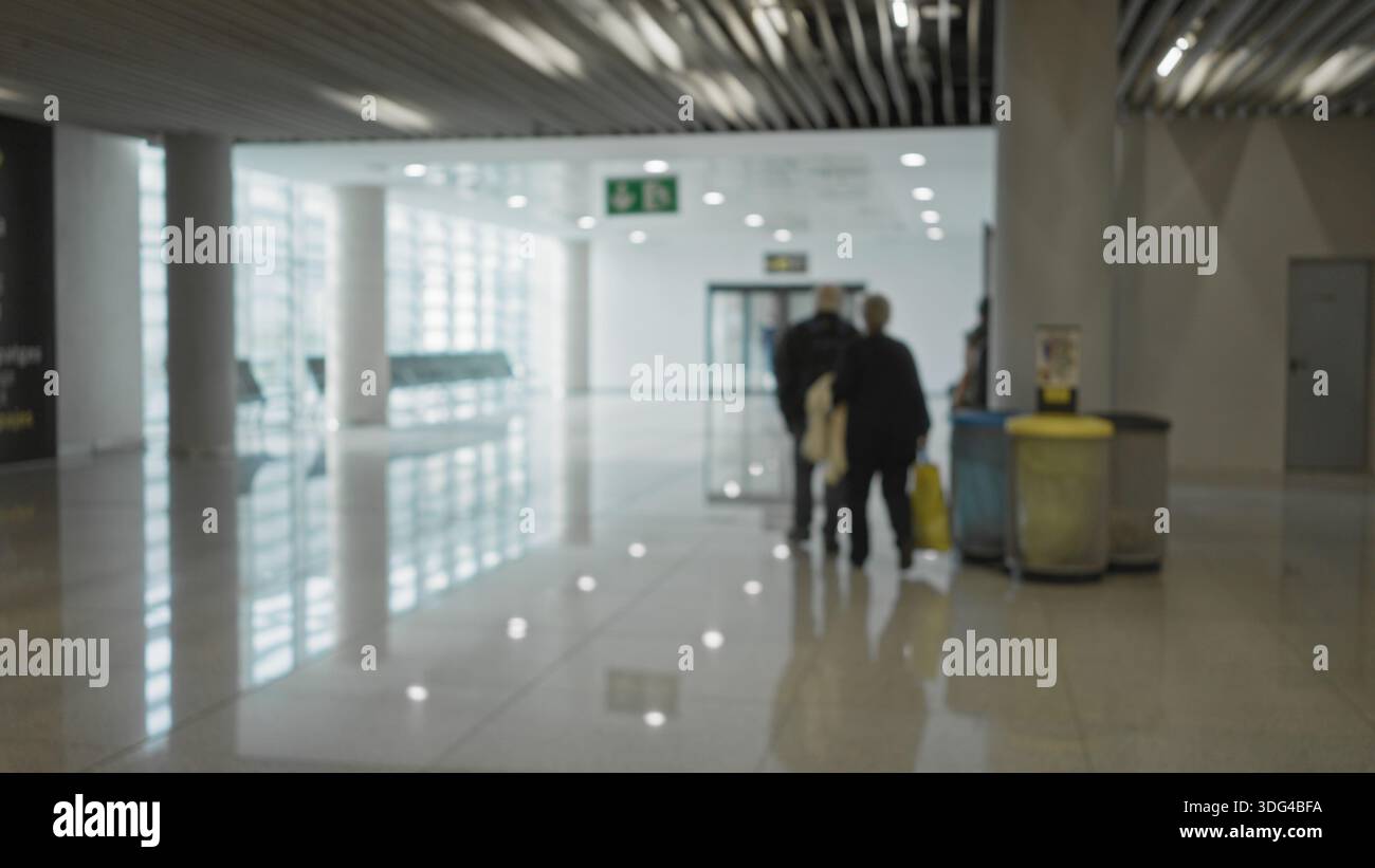 Blurred travelers walk through an airport terminal, featuring modern ...