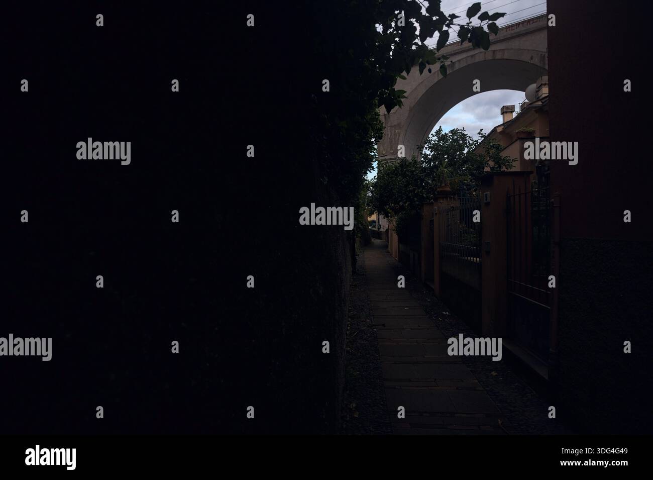 Narrow alley under the arches of a bridge in an italian town at sunset ...