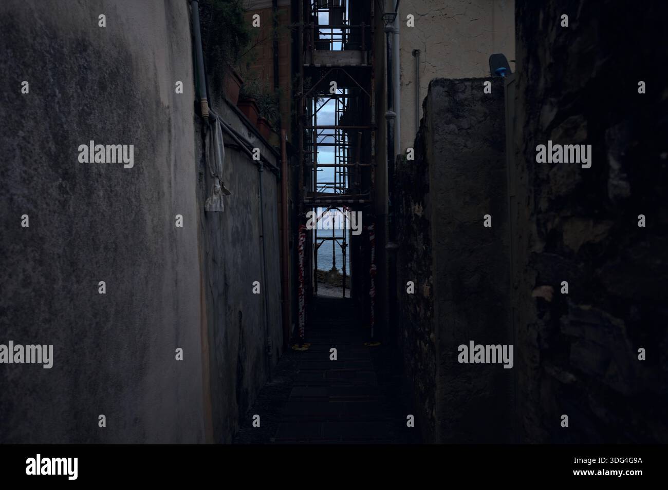 Narrow alley between tall buildings with a scaffolding hindering the ...