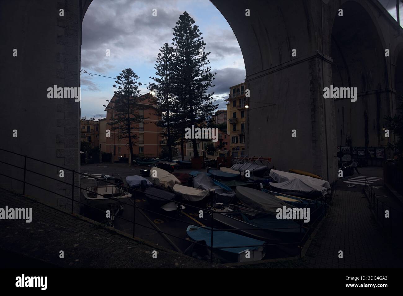 Square under the arches of a bridge with trees and covered boats in an ...